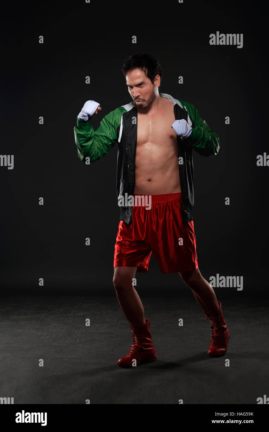 Muscular asian male boxer training uppercut punching over black ...