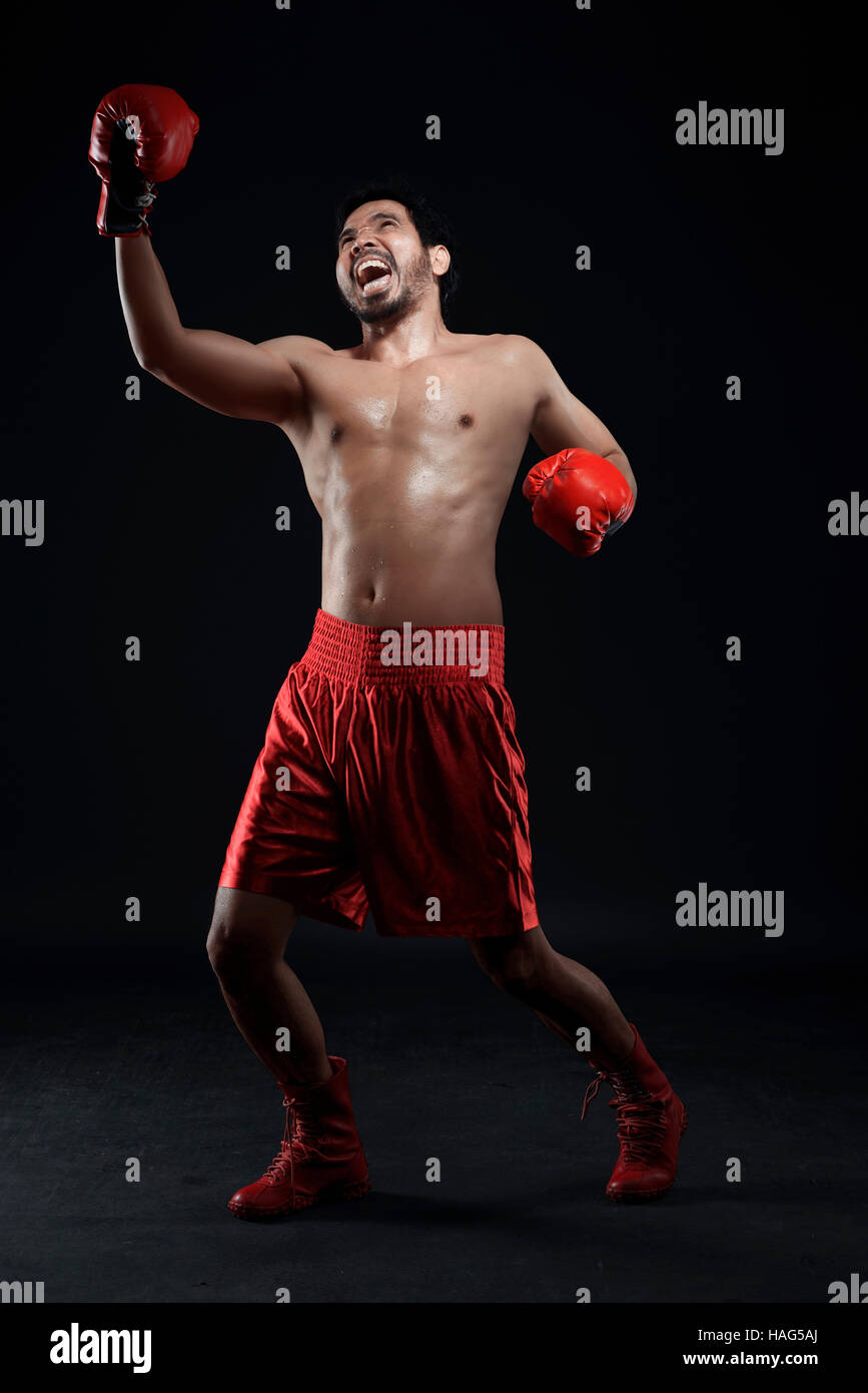 Asian boxer celebrating a win with boxing gloves against black ...