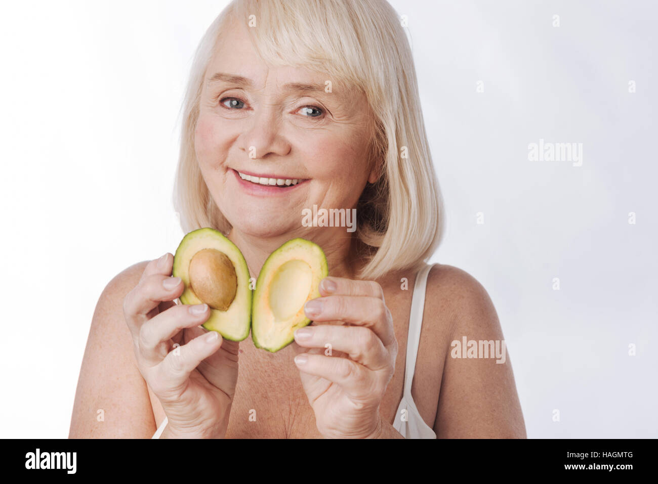 Nice delighted woman putting two avocado halves together Stock Photo ...