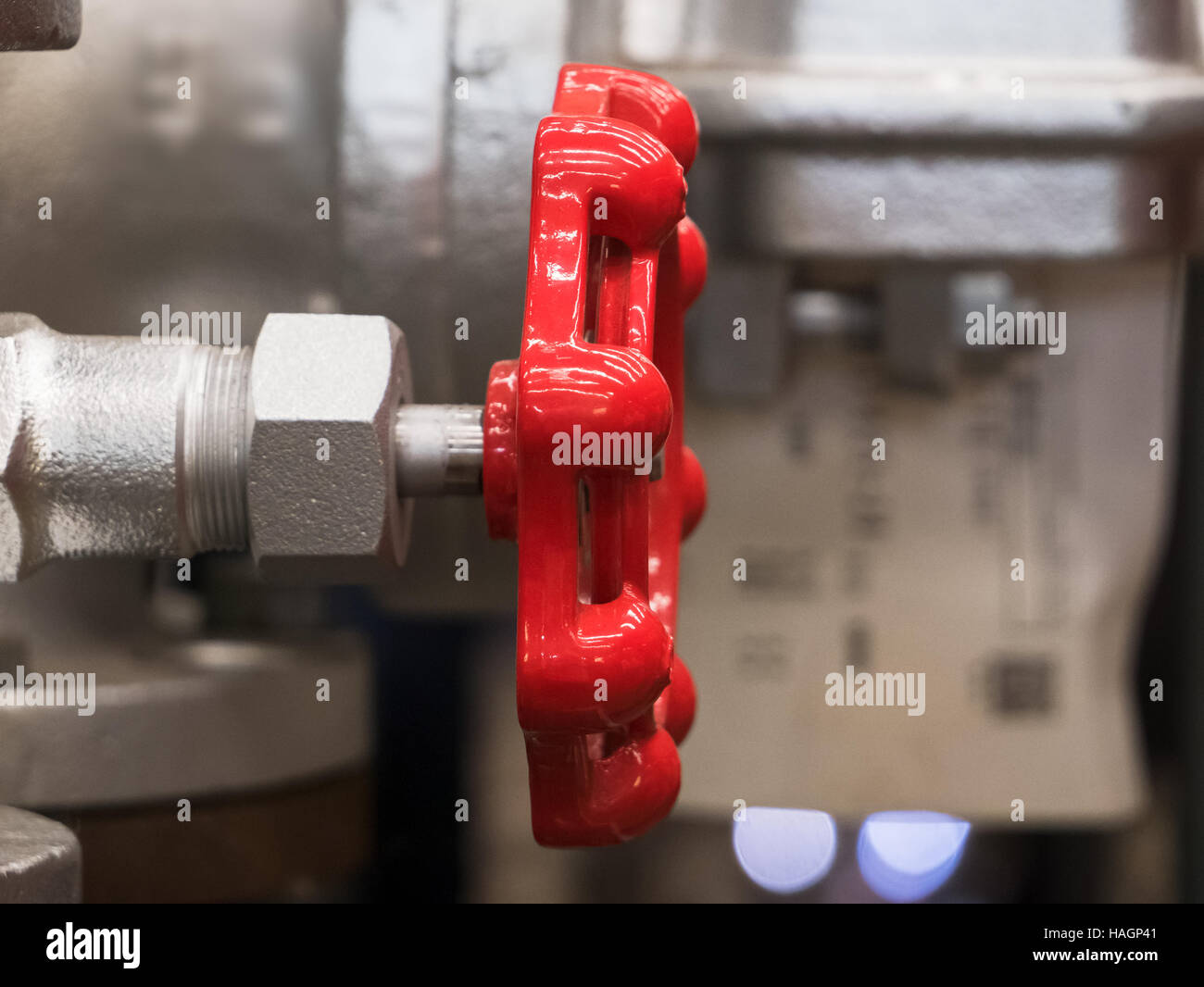 Red valve handle in industrial environment. Shallow depth of field with ...