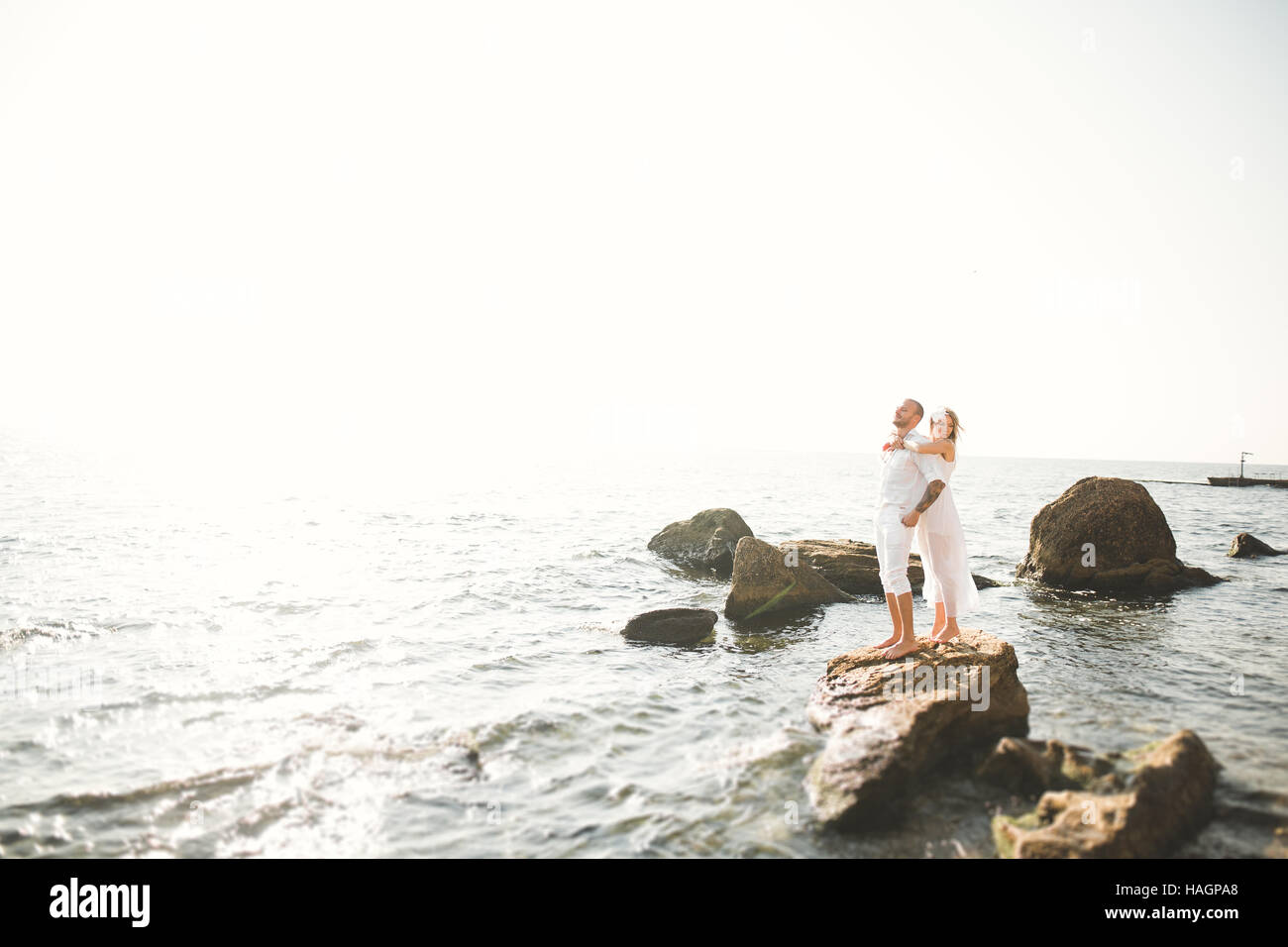 Wedding couple kissing and hugging on rocks near blue sea Stock Photo ...