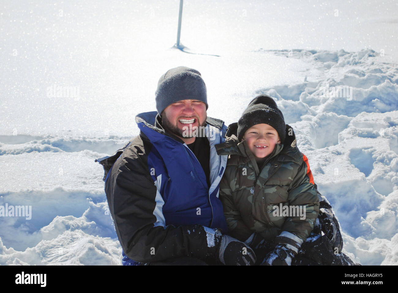 Portrait of handsome dad and his cute little boy sitting in the snow ...