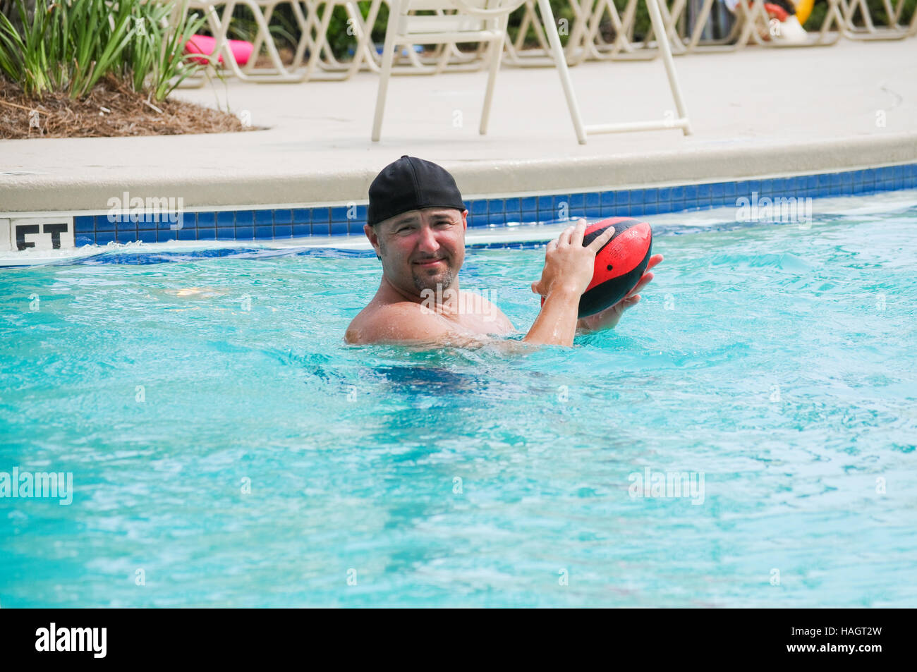Middle aged handsome man holding football in swimming pool Stock Photo ...