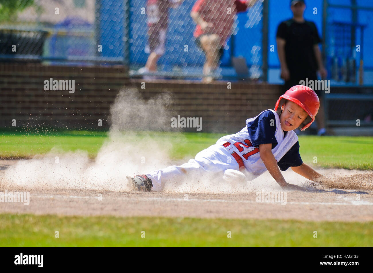 Youth baseball player sliding in at home Stock Photo - Alamy