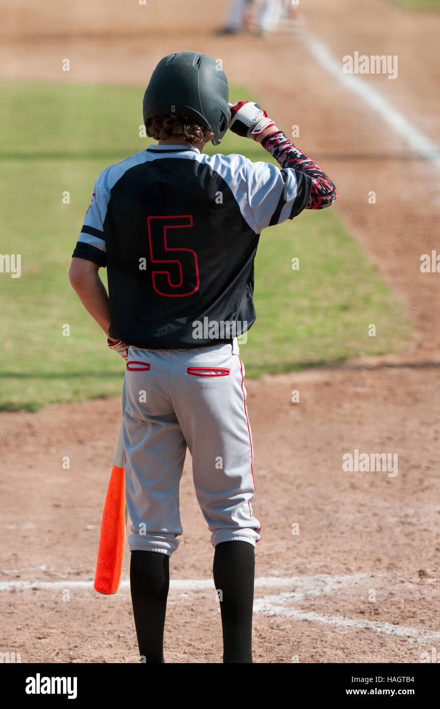 Teen baseball player from behind holding a bat at home plate during a ...