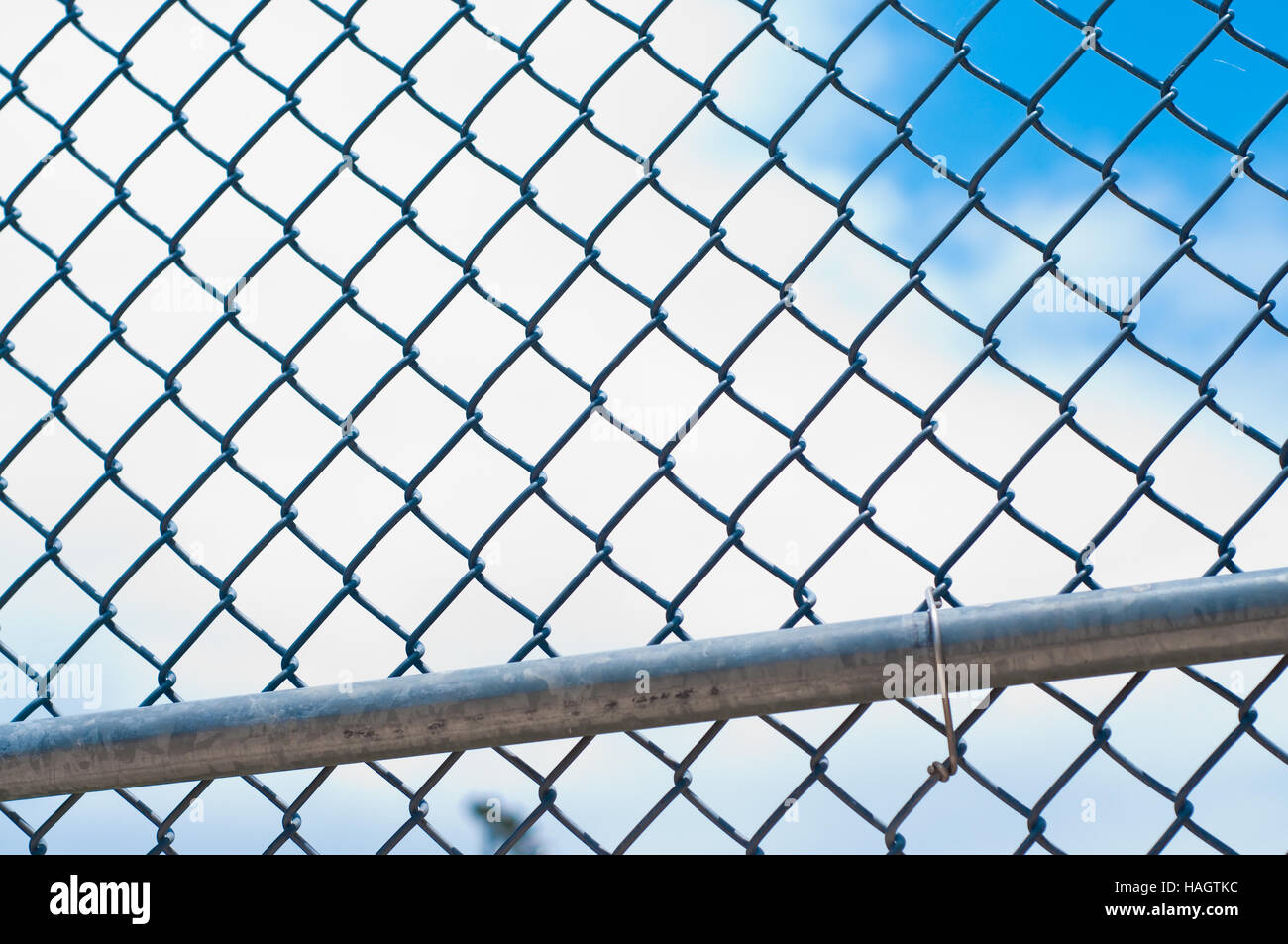 Baseball chain link fence with blue sky and white clouds in background ...