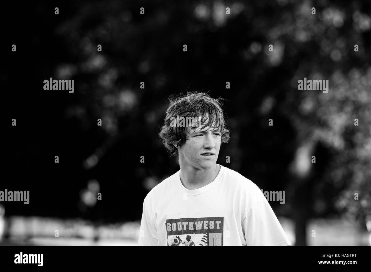 Handsome teenage boy outside looking sideways with blank expression ...
