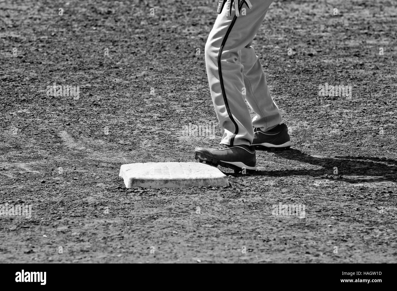 Close up in black and white of baseball base with player standing on it ...