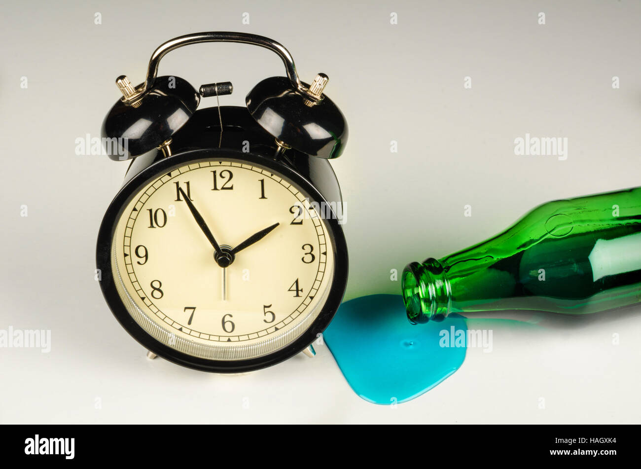 Hangover concept with an alarm clock and a bottle spilling a fancy ...