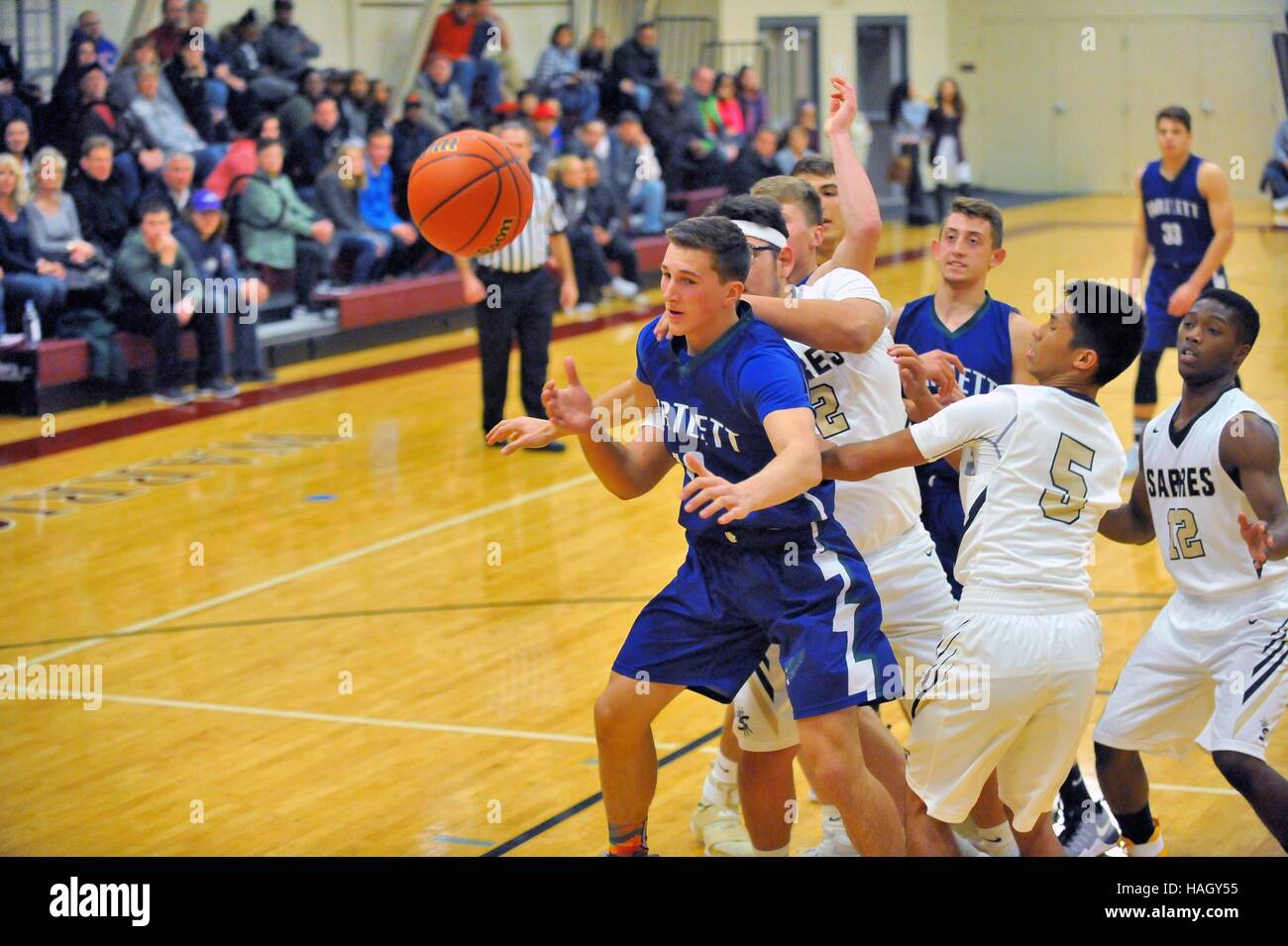 Player trying to secure a loose ball under the basket while screening ...