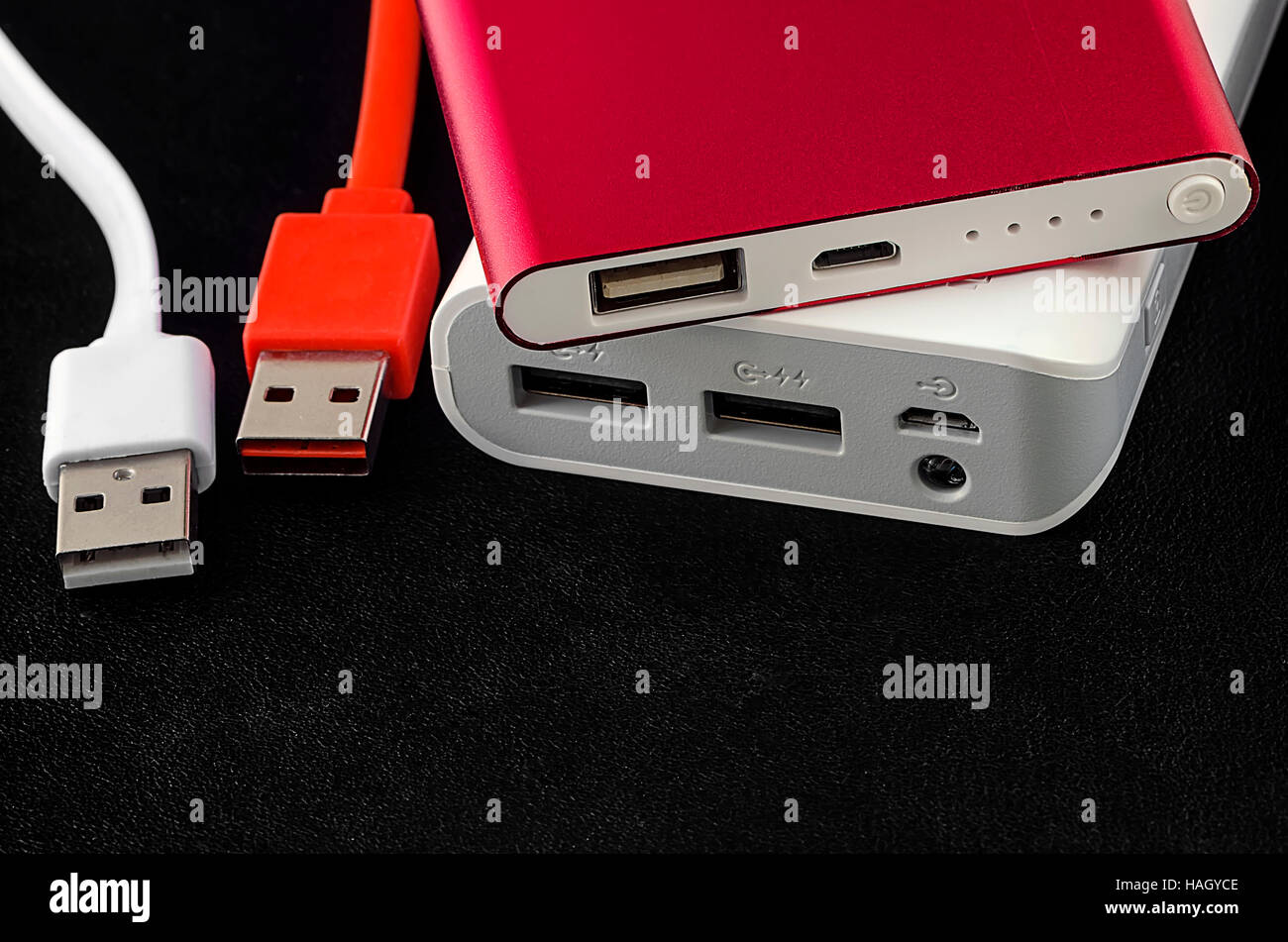 Red and white power bank with usb cable on black leather background ...
