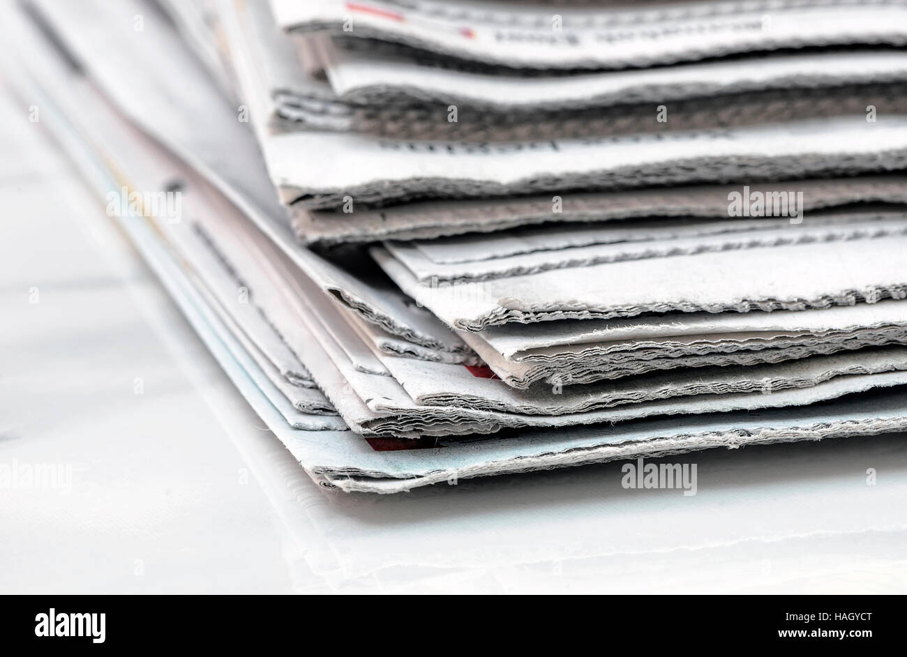 Stack of newspaper on white table Stock Photo - Alamy