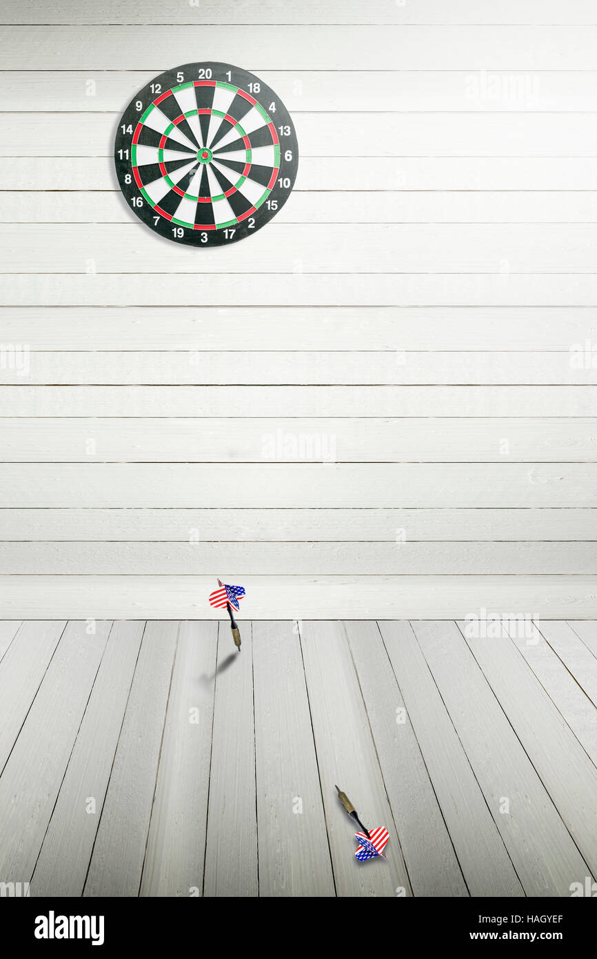 Darts board on wooden wall and darts miss the target drop on the ground ...