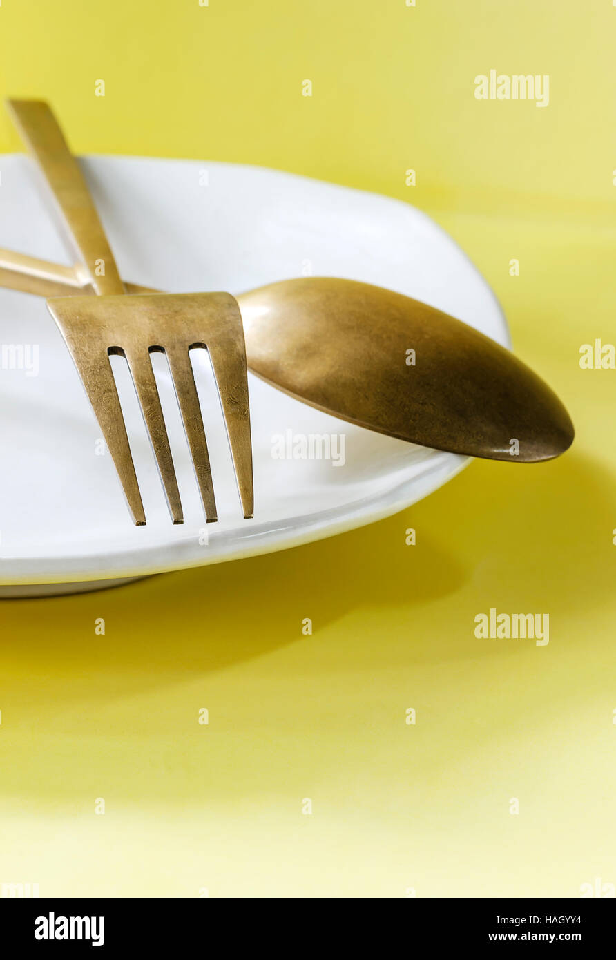Old brass spoon and fork on the white dish ,yellow background,soft ...