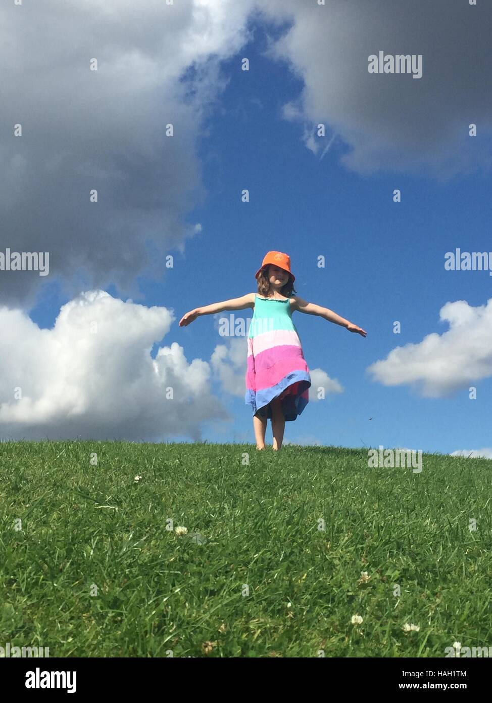 Girl with arms out standing on hill wearing sundress in summer Stock ...