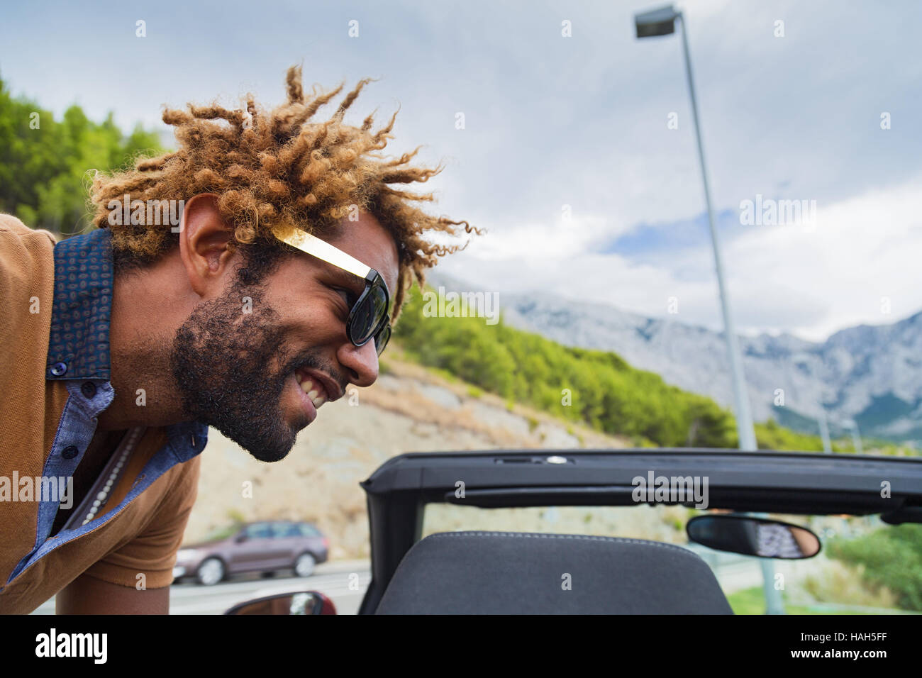 Young happy black man with dread locks wearing sunglasses leaning over ...
