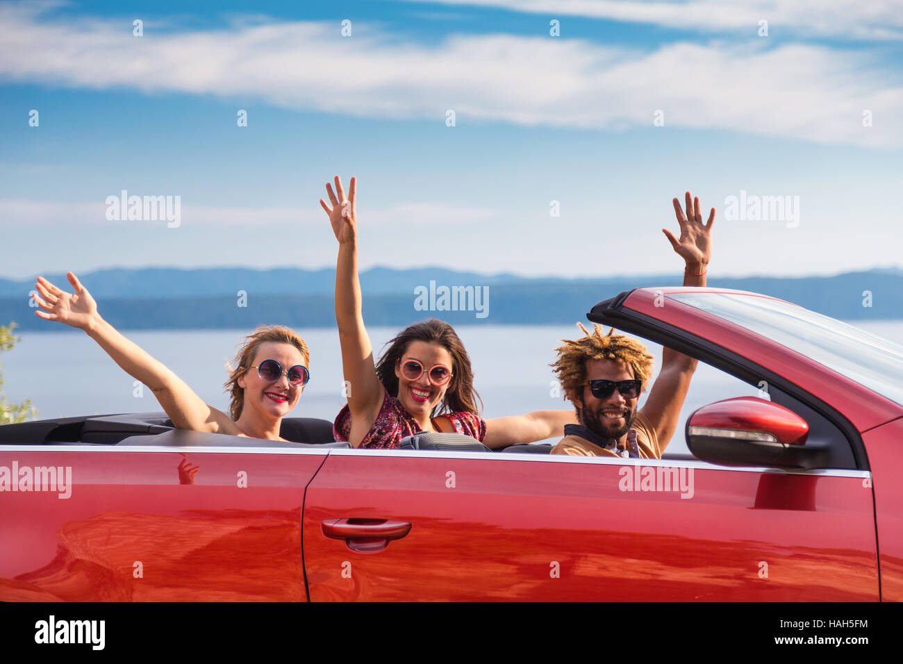 Group of happy young people waving from the red convertible Stock Photo ...