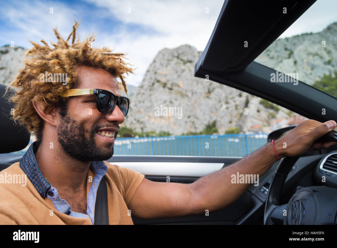 Young happy black man with dread locks wearing sunglasses sitting in ...