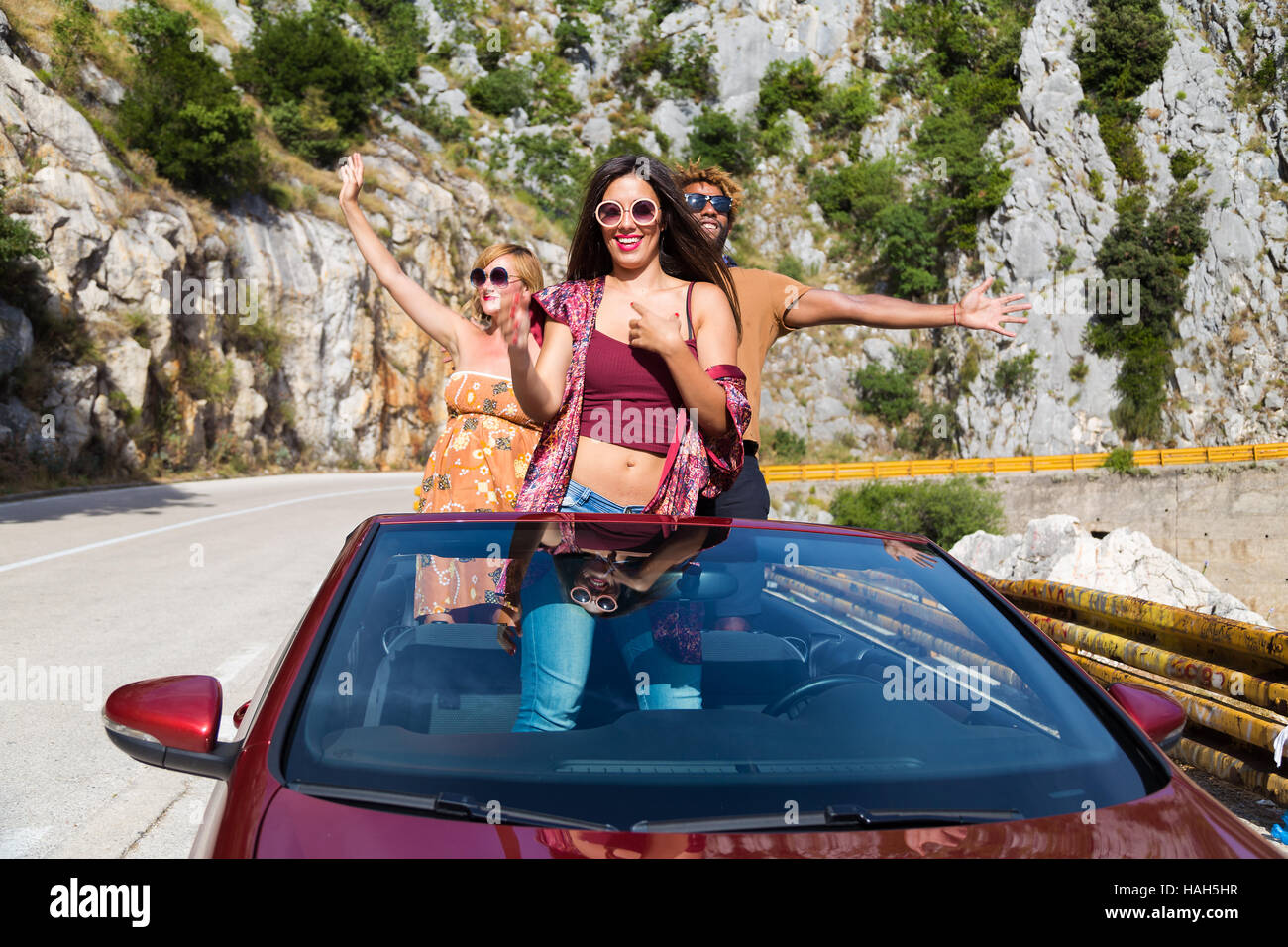 Group of happy young people waving from the red convertible Stock Photo ...