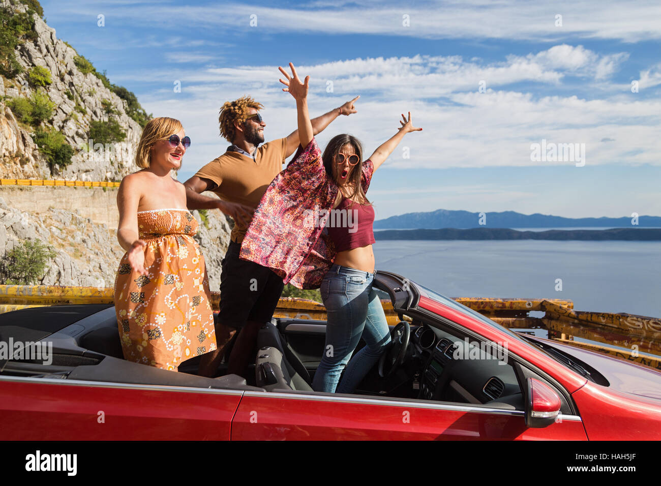Group of happy young people waving and pointing fingers from the red ...