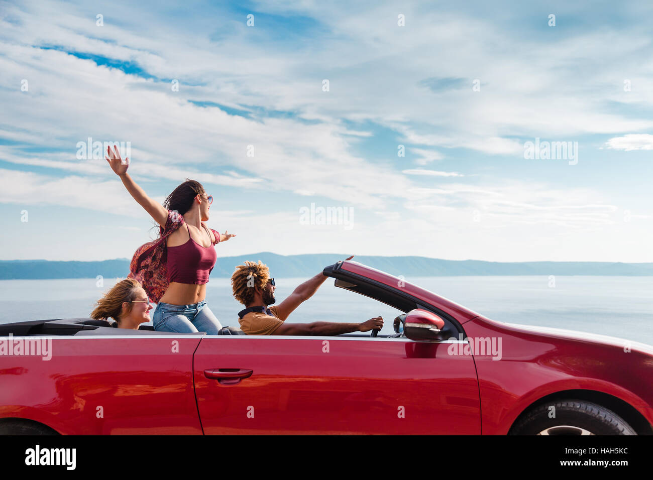 Group of happy young people waving from the red convertible Stock Photo ...