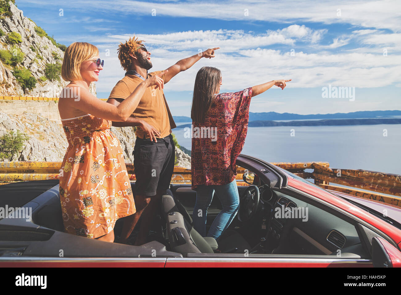 Group of happy young people waving and pointing fingers from the red ...