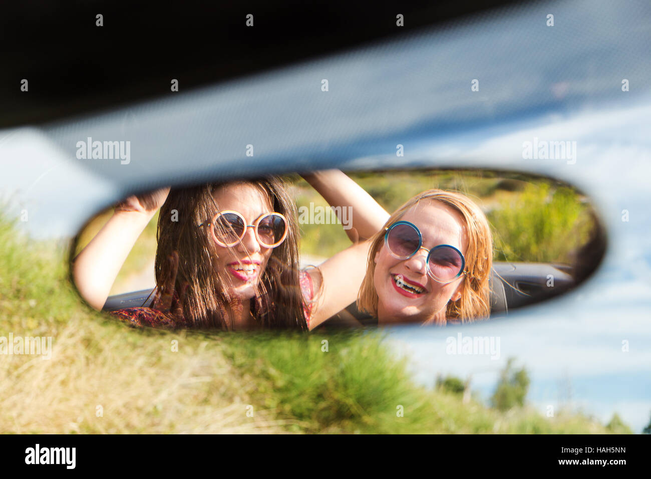 Two happy girls in a car rear-view mirror Stock Photo - Alamy