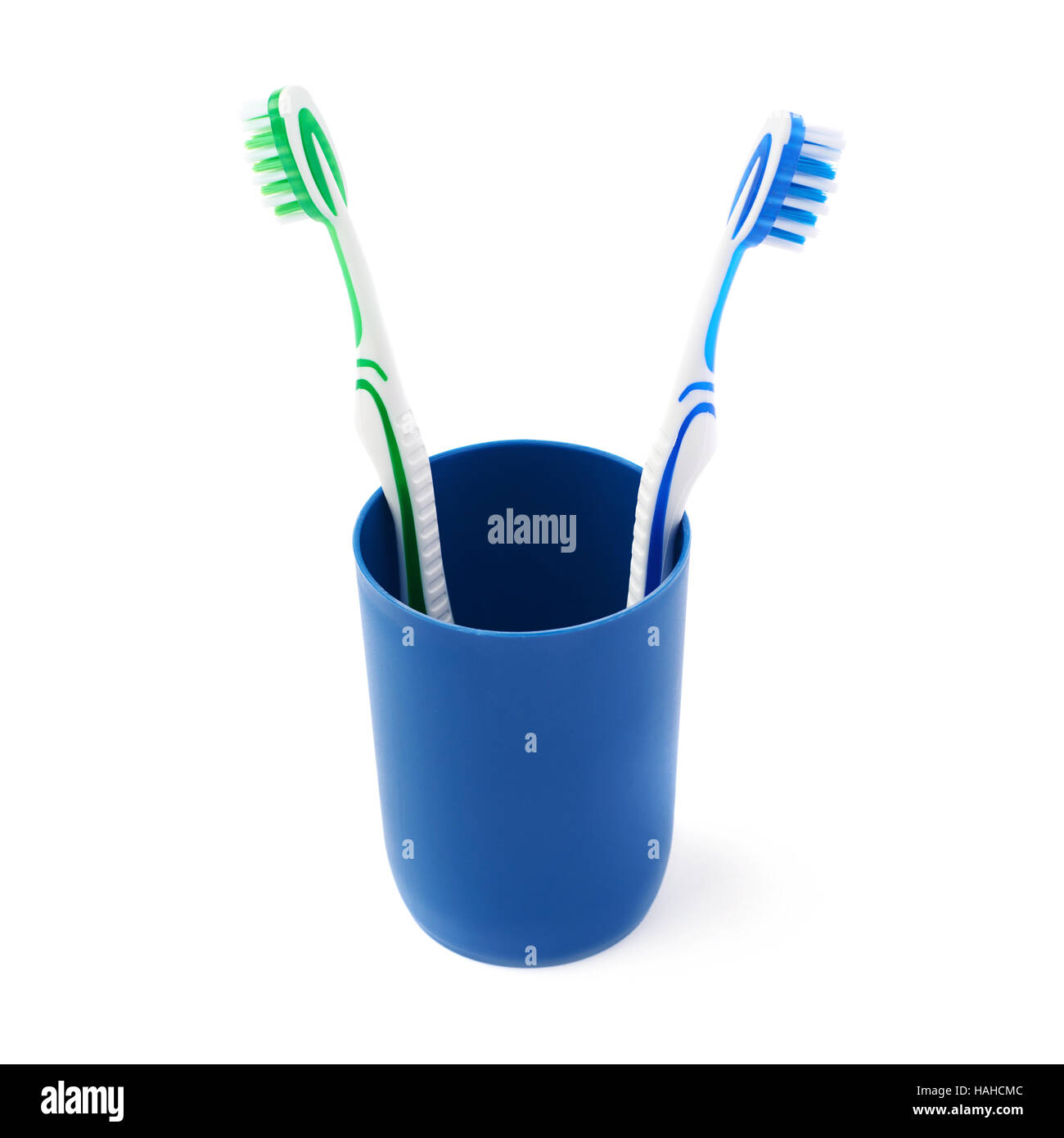 Pair of green and blue toothbrushes in blue plastic cup isolated over ...