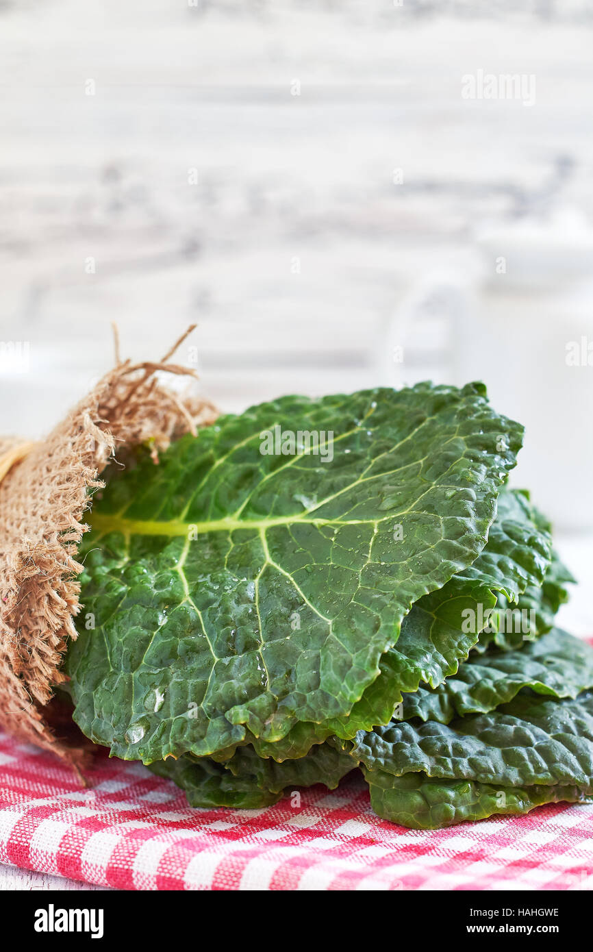Raw organic savoy cabbage leaves on white rustic wooden background ...