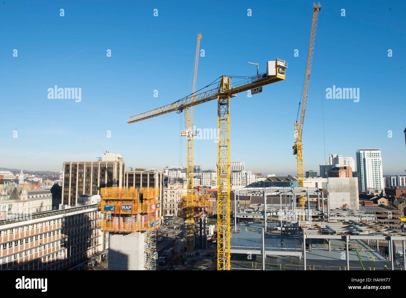 Yellow cranes over a building construction site with a dark blue sky in ...