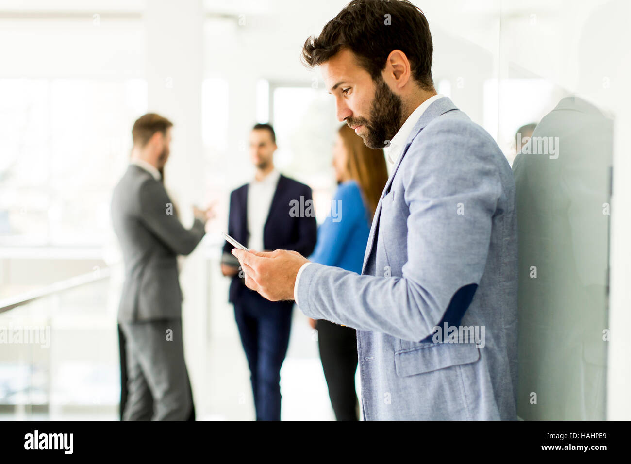 Businessman using mobile phone in office while other business people ...
