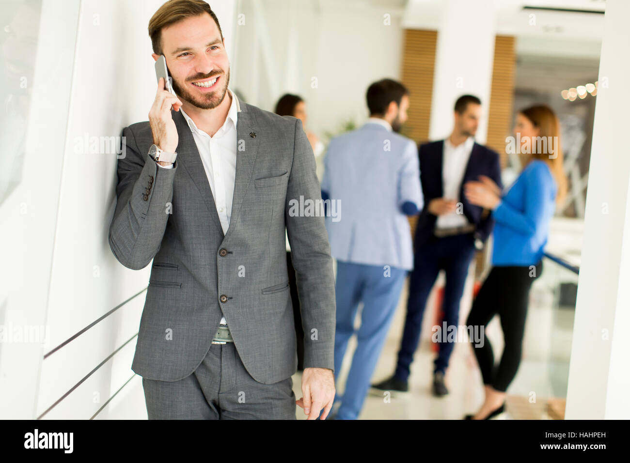 Businessman using mobile phone in office while other business people ...