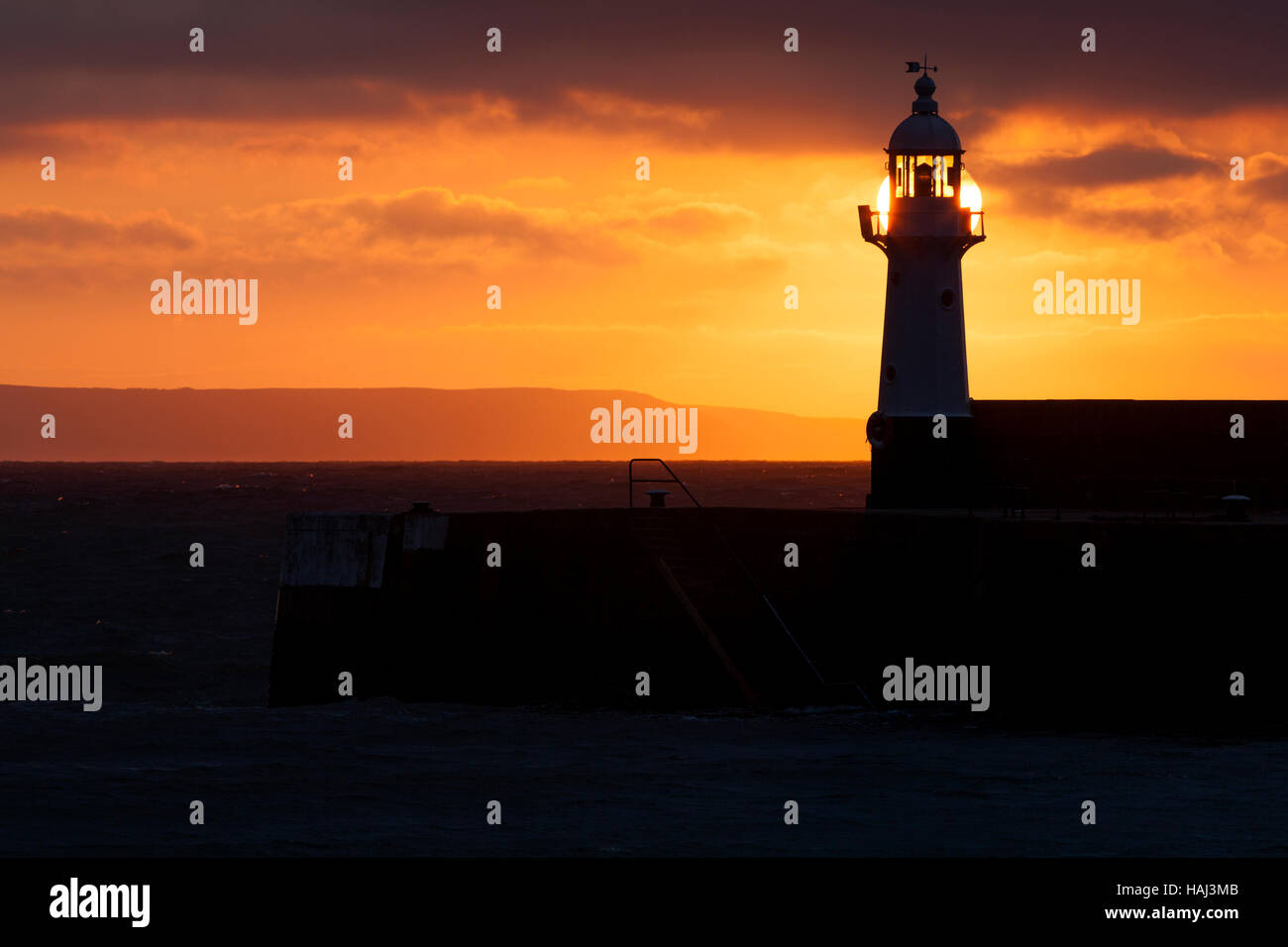 Lighthouse at Sunrise with the sun behind, silhouette and gold/orange ...
