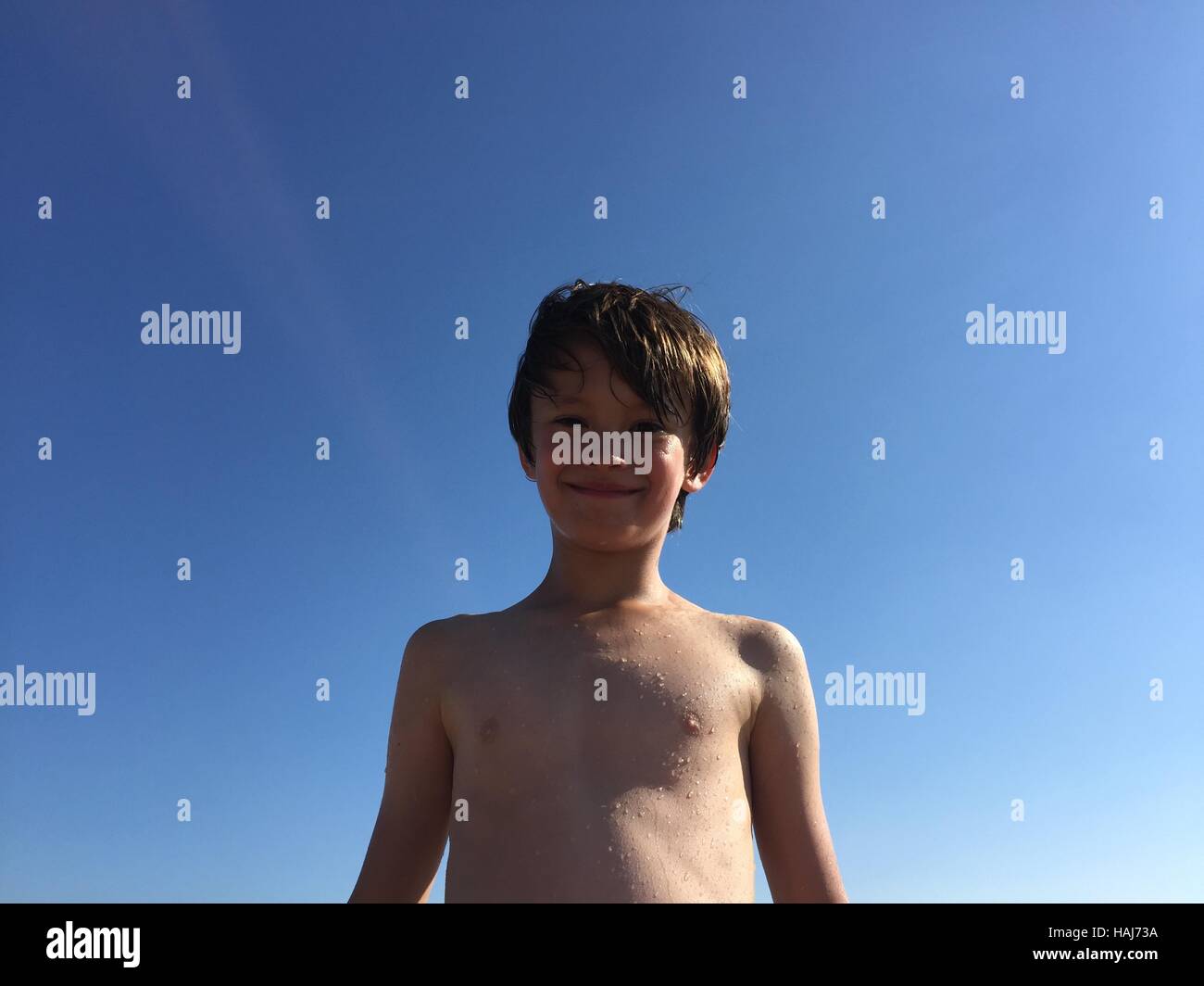 Bare chested boy against clear blue sky Stock Photo - Alamy