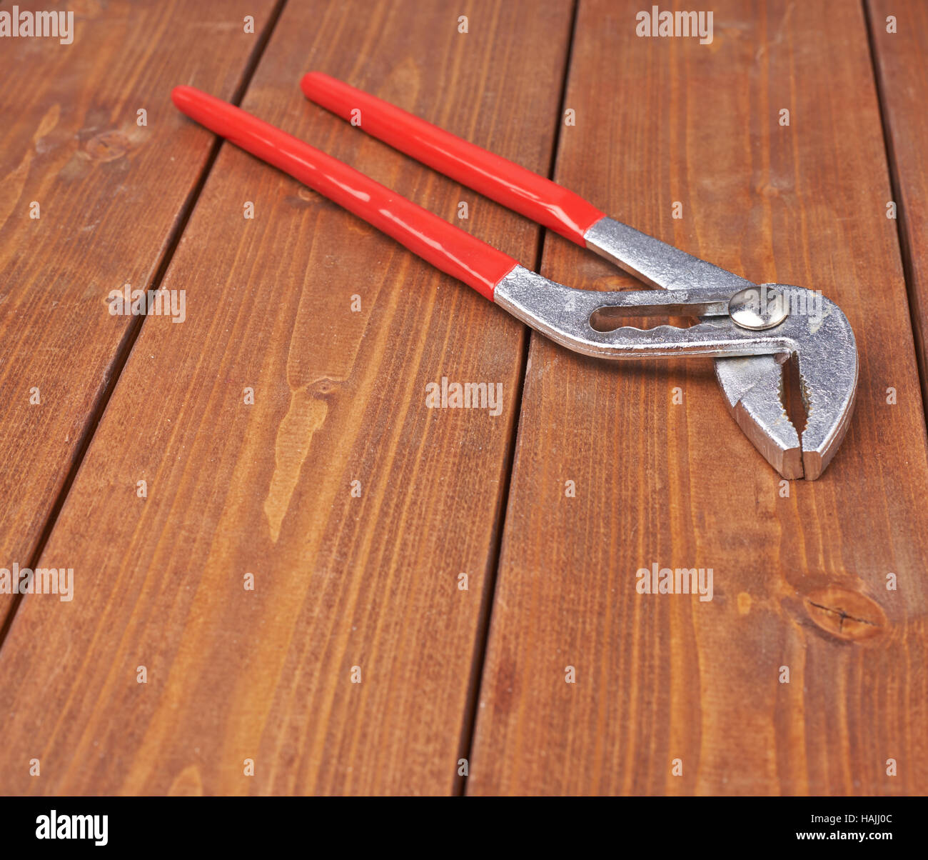 Metal plumber wrench with red handles on wooden surface Stock Photo - Alamy