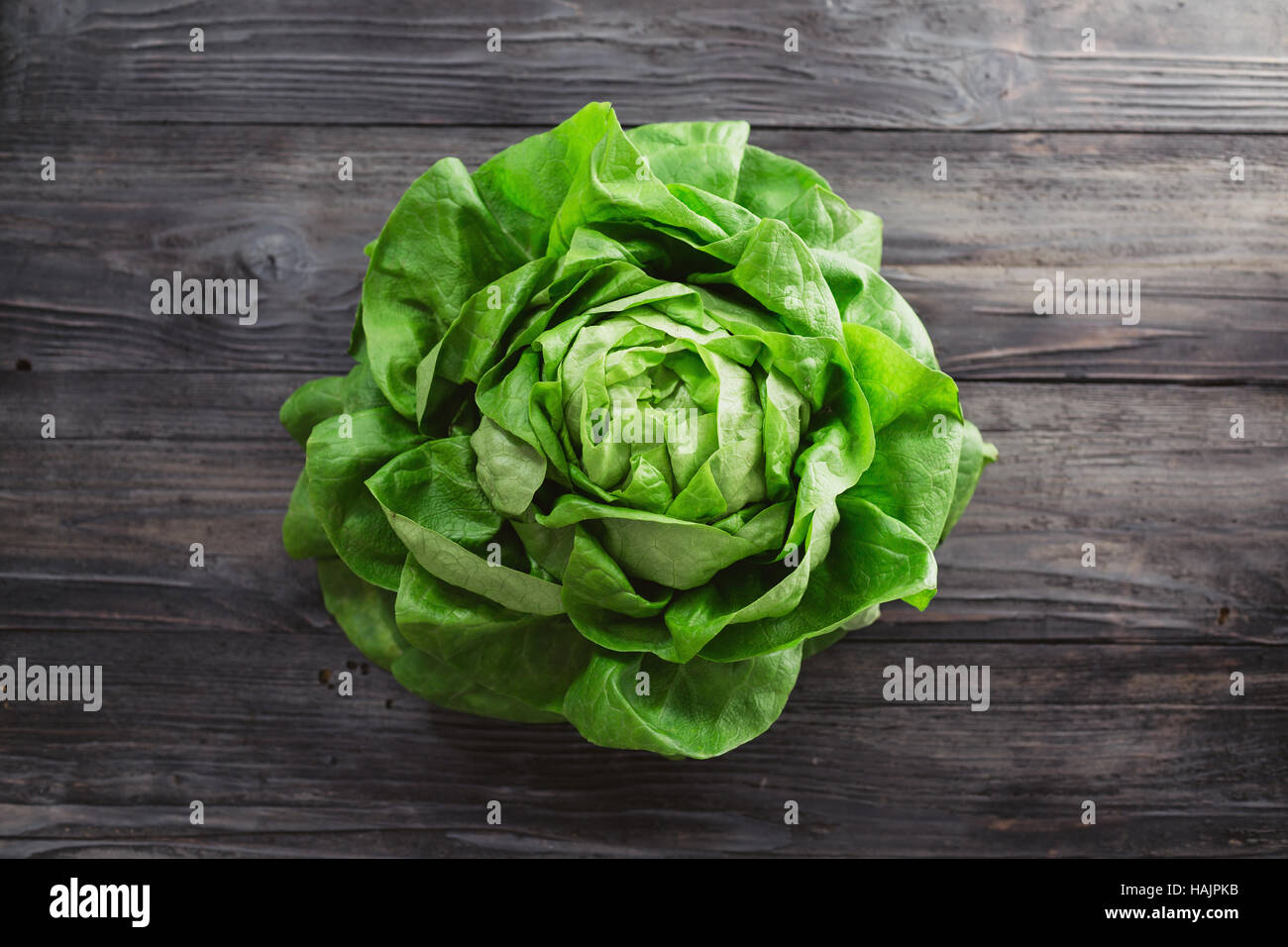 Single lettuce head over rustic wooden background Stock Photo - Alamy