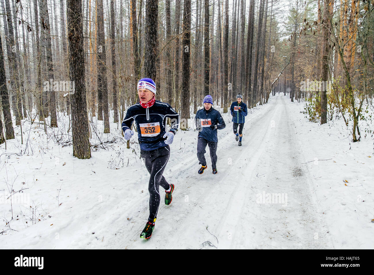group of male runners running snowy forest, snow falls during Winter ...