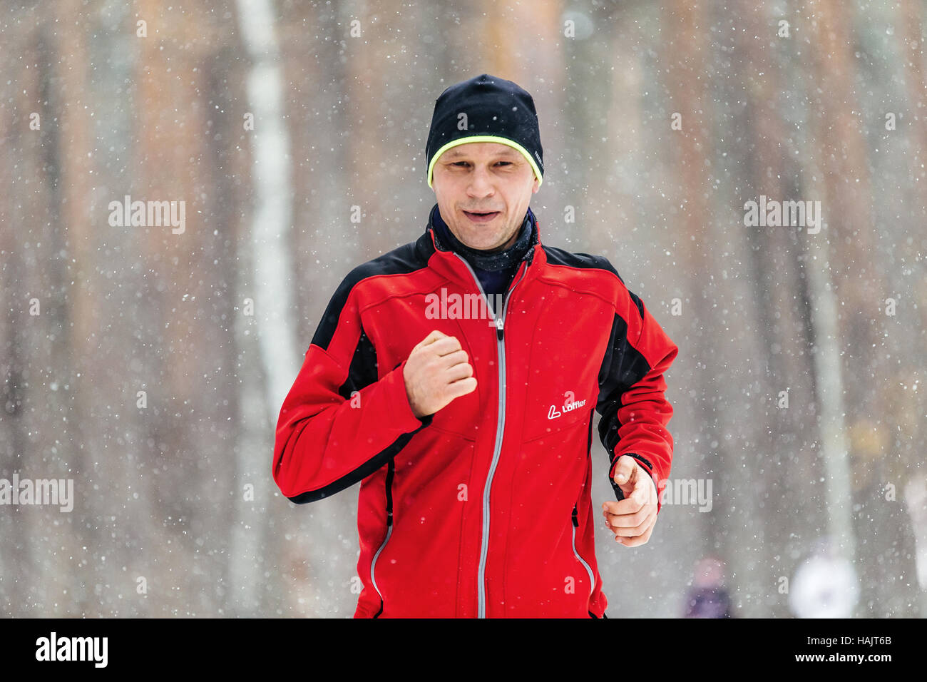 closeup male runner running in falling snow in forest during Winter ...