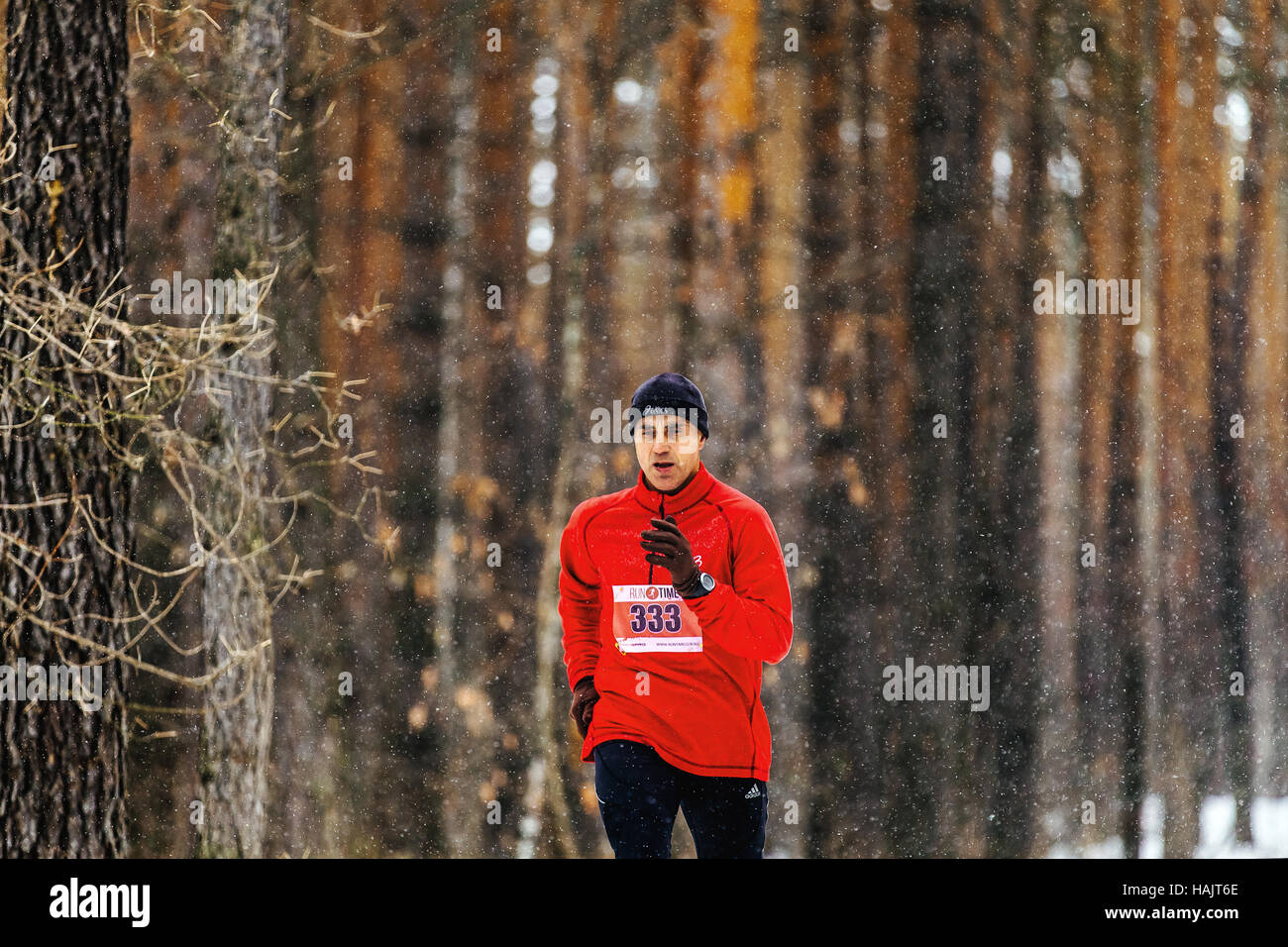 young male runner running in falling snow in forest during Winter ...