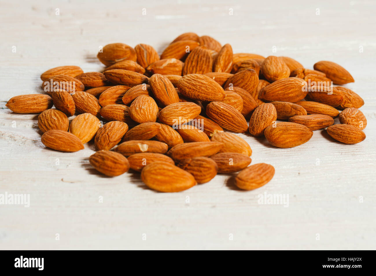 handful of almonds on a white wooden background Stock Photo - Alamy