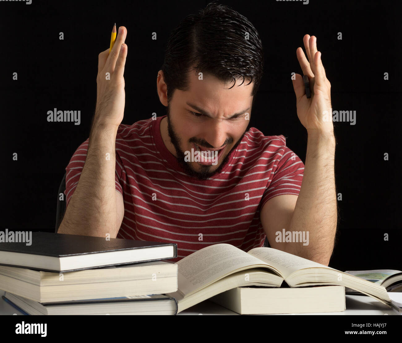 Frustrated man with studies. Many books and black background Stock ...