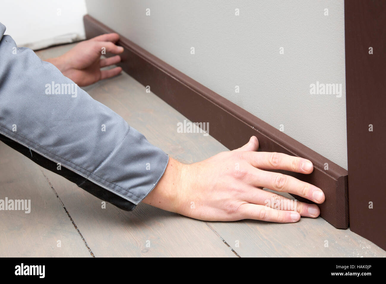 installation of a brown wooden baseboard at the bottom of the wall ...