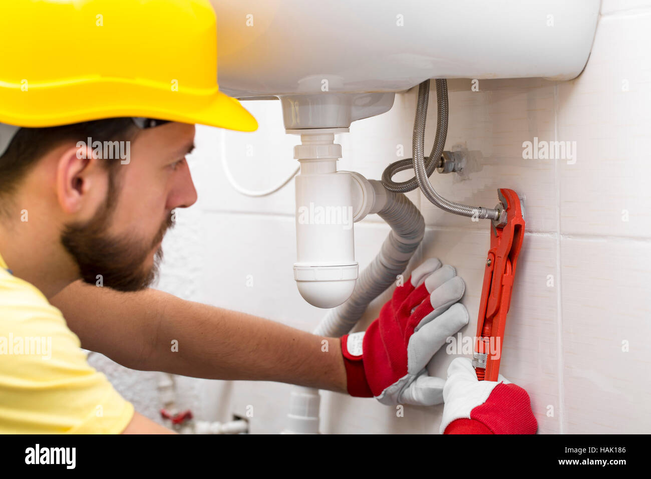 plumber fixing sink pipe with wrench in bathroom Stock Photo - Alamy