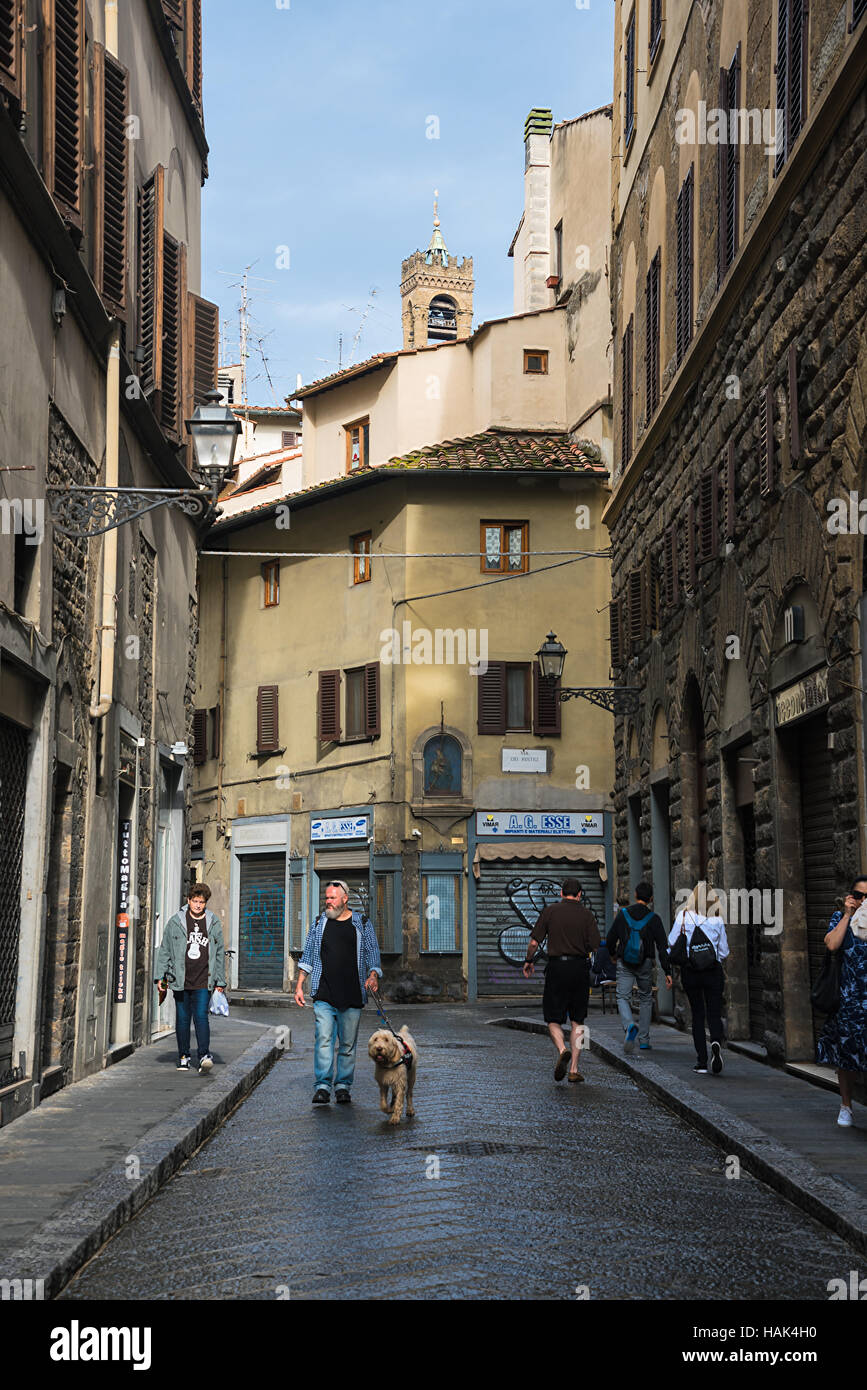A man with dog walking on the old street of Florence, capital of ...