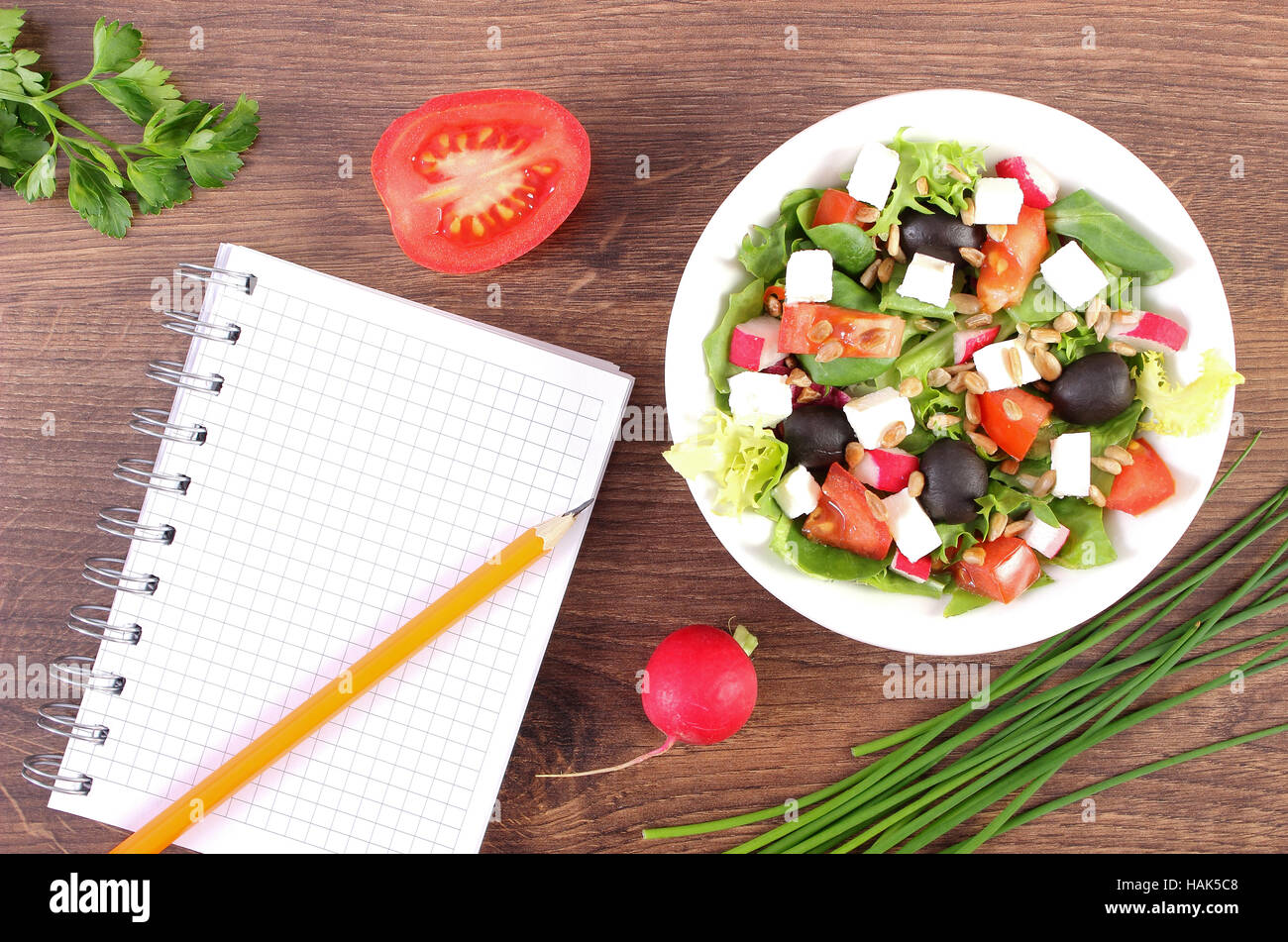 Fresh greek salad with vegetables and notepad for writing notes ...