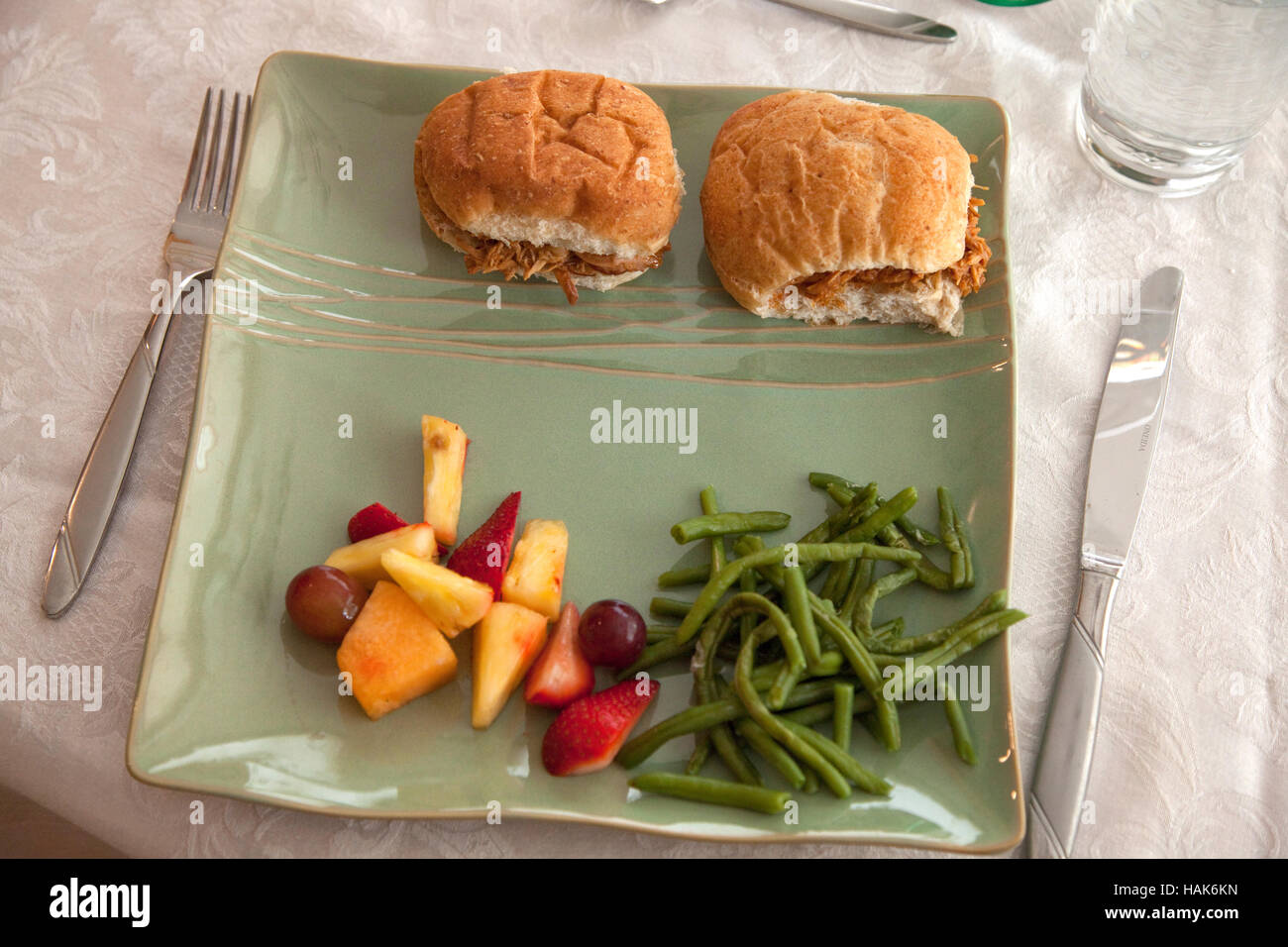 Dinner plate with pulled pork bun sandwich, fruit and green beans ...