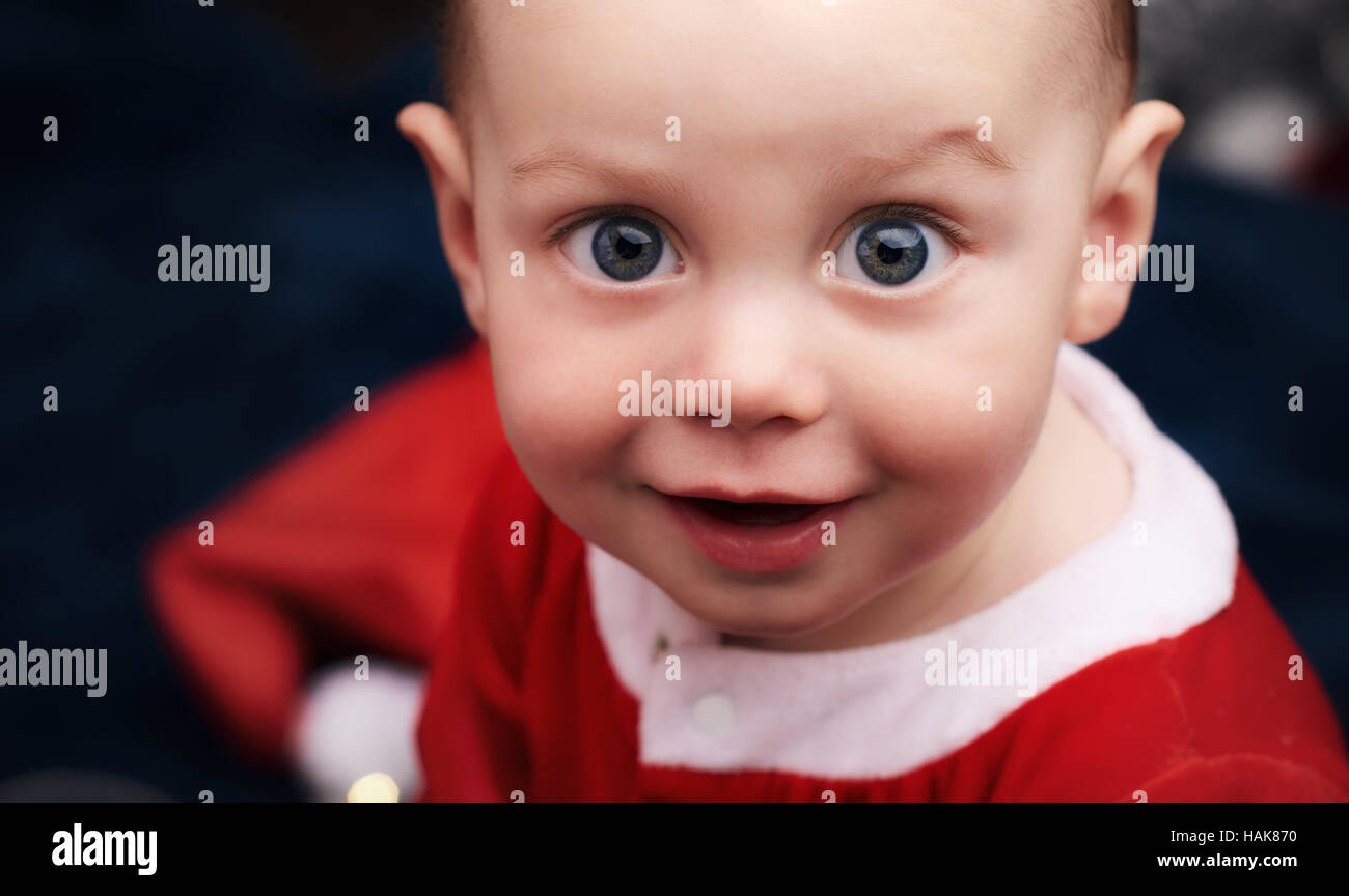 Santa baby smiling up at camera with hat in background Stock Photo - Alamy