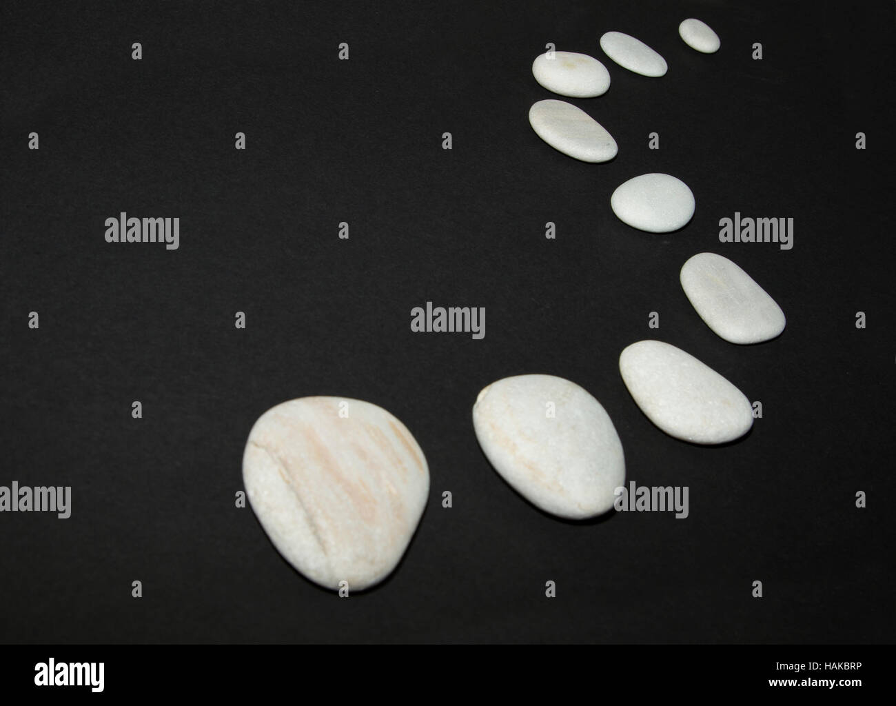 White or gray pebble stones in line on black background Stock Photo - Alamy