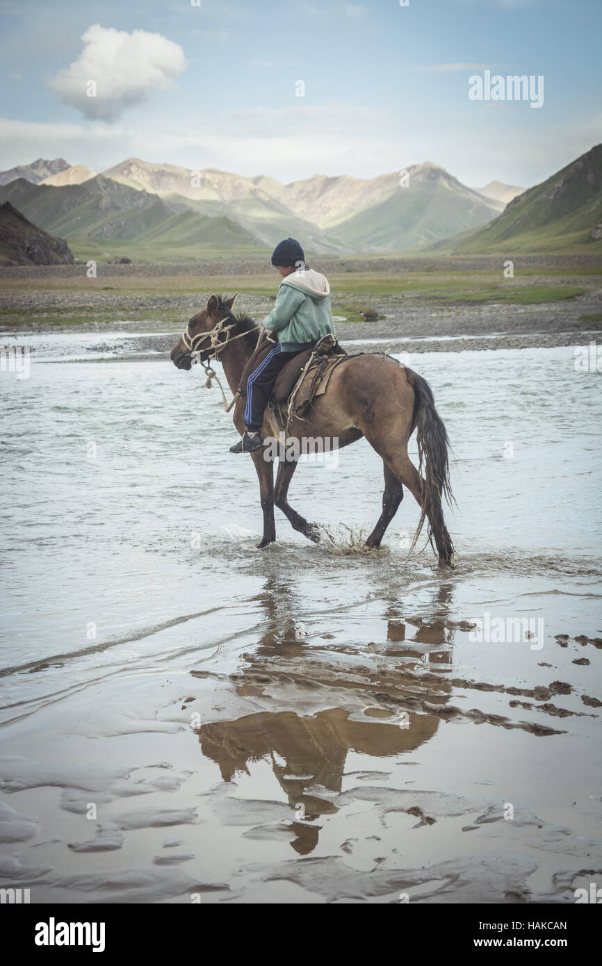 Young boy riding his horse in the evening, to the other side of a ...