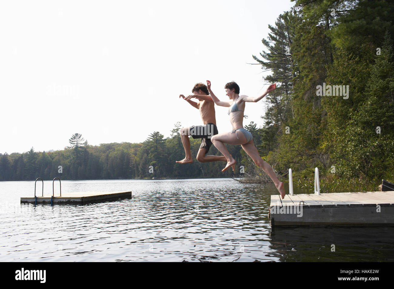 Couple jumping water jetty hi-res stock photography and images - Alamy